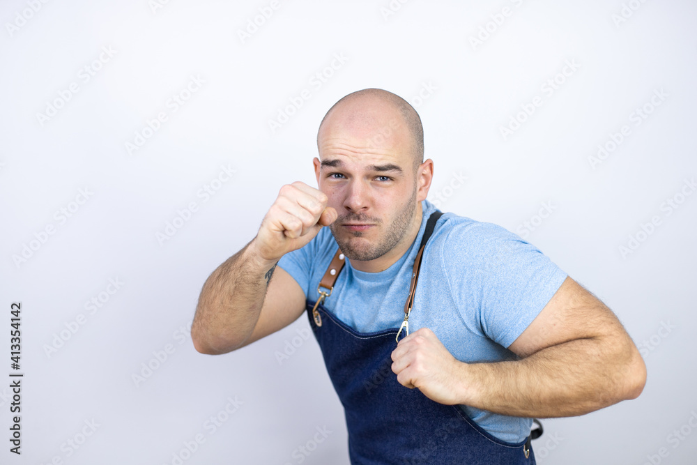 Young bald man wearing apron uniform over isolated white background ...
