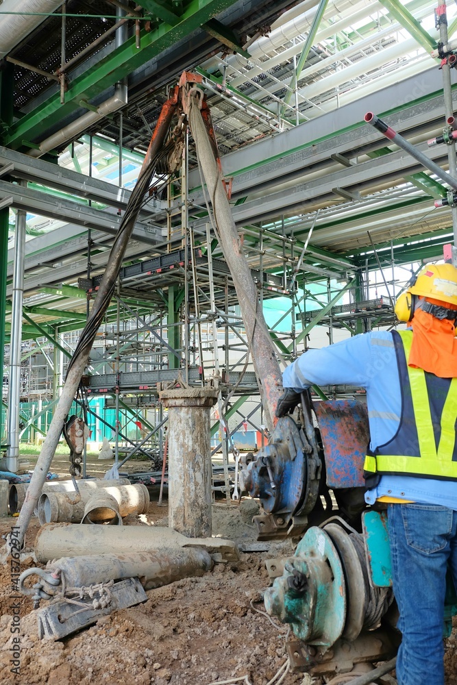 Workers are controlling the tripod rig machine is drilling holes in the ...
