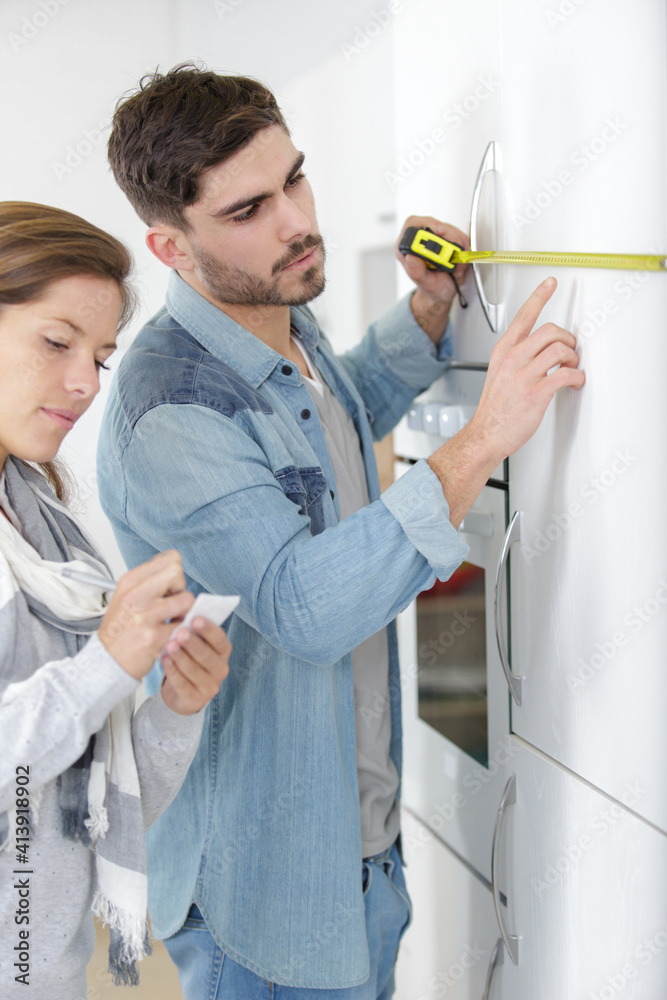 couple measuring kitchen cabinet with tape ruler Stock Photo | Adobe Stock