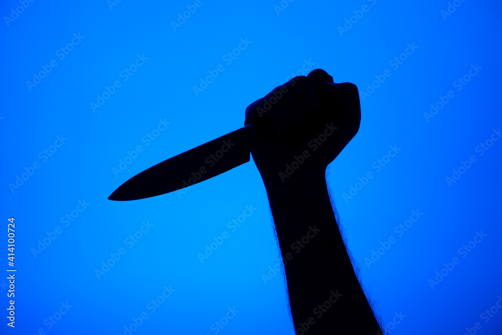 Knife stabbing gesture silhouette black on blue background studio shot ...