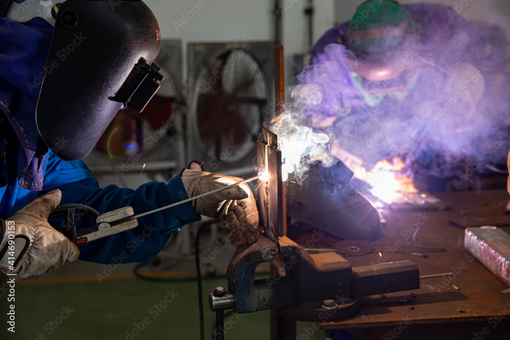 Two welder are assembling the workpiece by process shielded metal arc ...