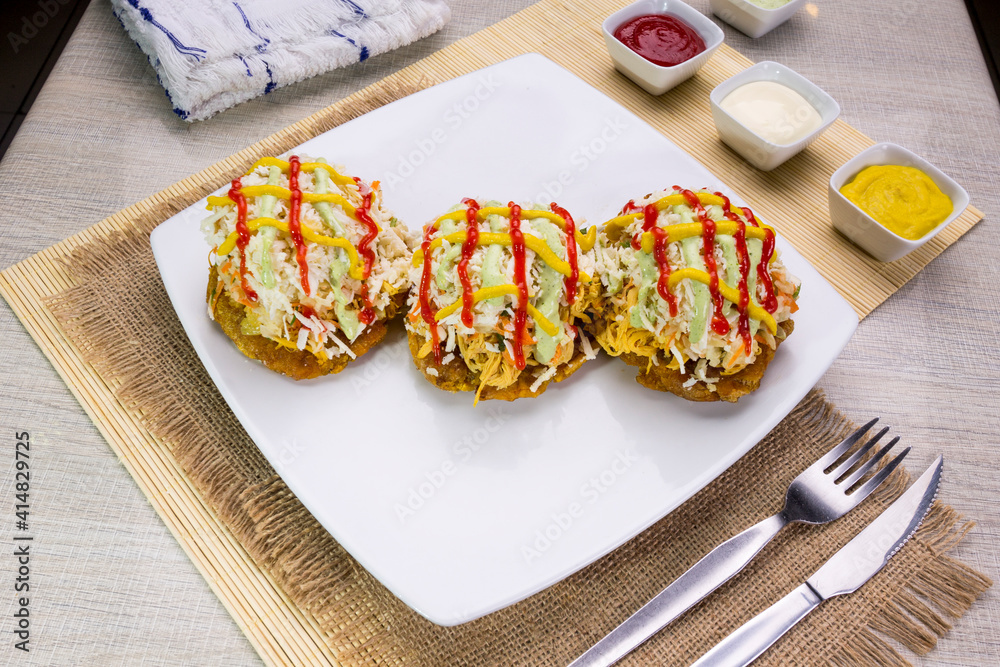 Plato de comida venezolana hecho de tostón con ensalada de col, queso ...