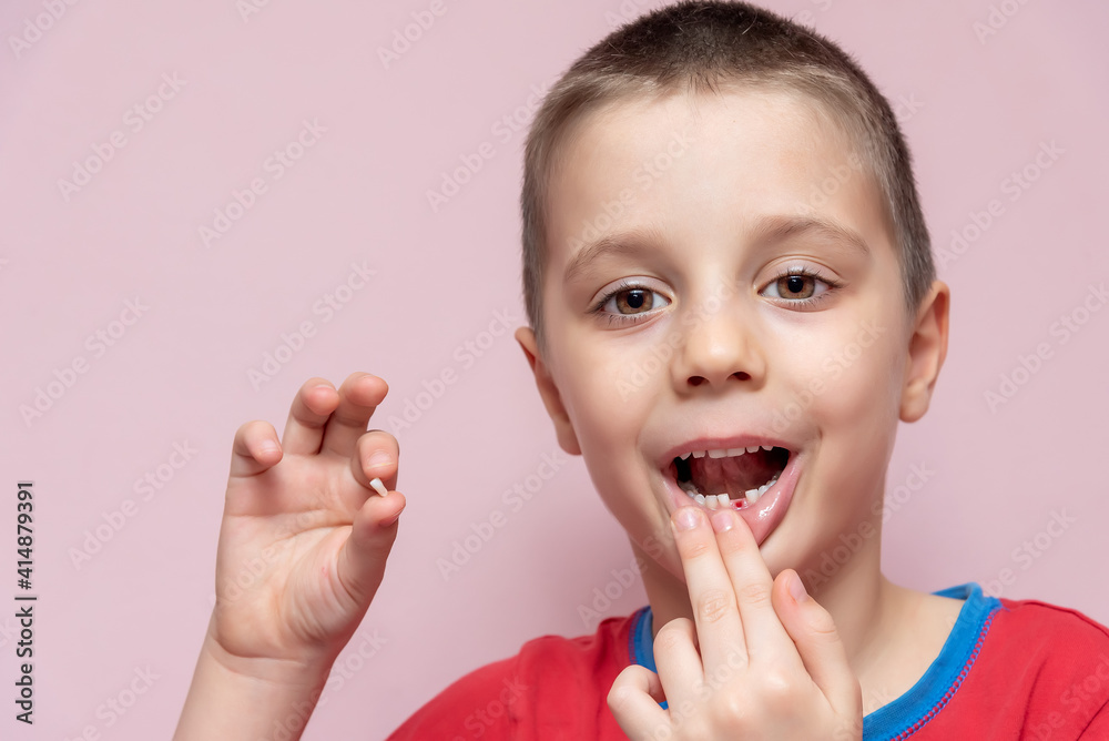 Cute elementary age boy is pulled his baby tooth with hand himself. He ...