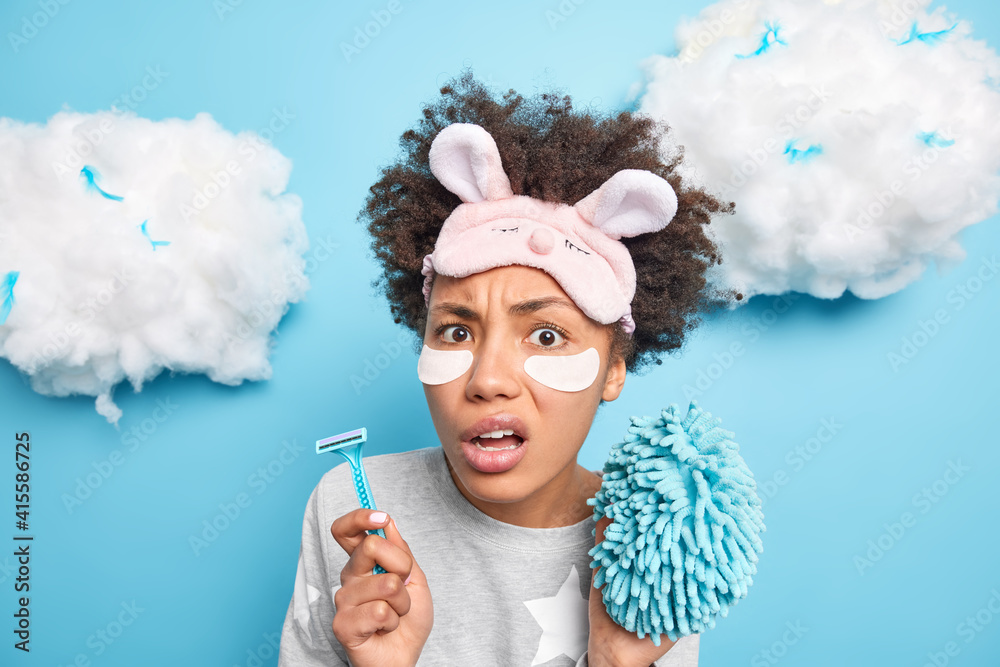 Beautiful puzzled African American woman holds razor and sponge going ...