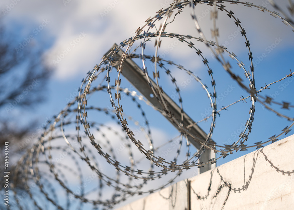 Close up sharp pointed razor wire barb fence coiled on top of prison ...