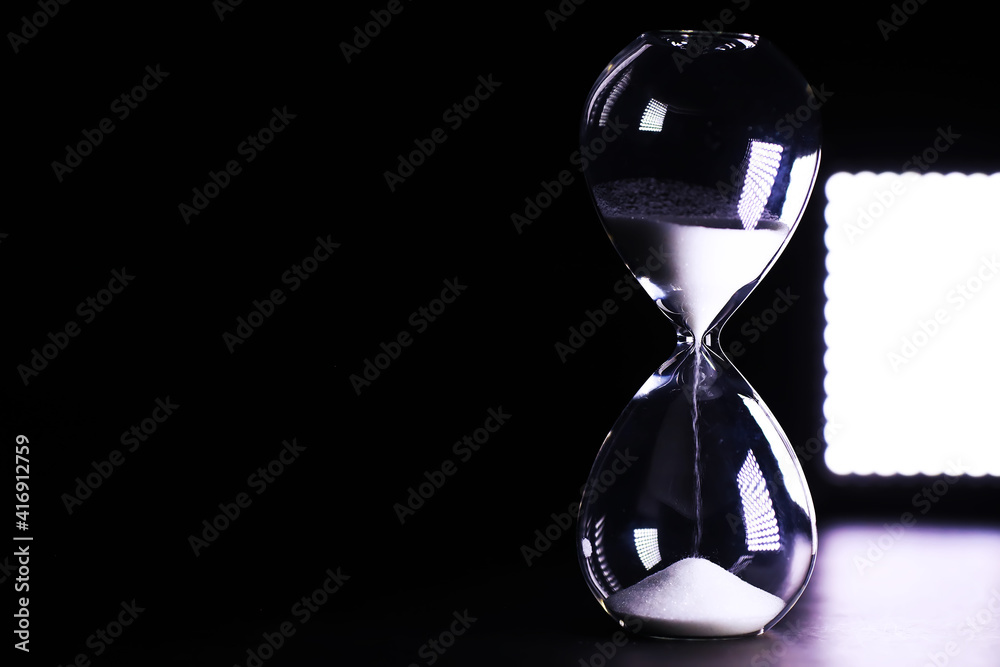 Sand running through the bulbs of an hourglass measuring the passing ...