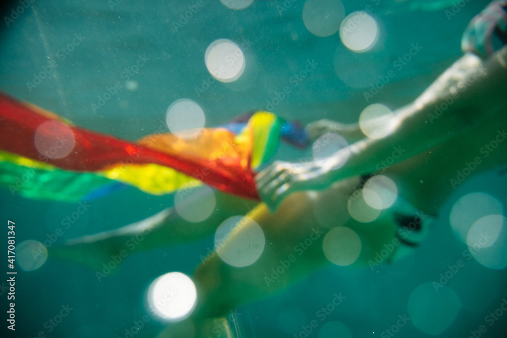 Horizontal view of unrecognizable woman swimming underwater holding a ...