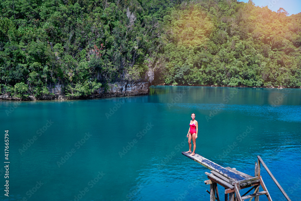 Vacation and activity. Young woman in swimsuit enjoying blue tropical ...