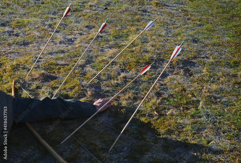 man lying on a frozen lawn hit by an arrow from a bow. archery range ...
