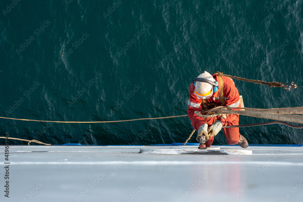 Seaman ship crew working aloft at height derusting and getting vessel ...