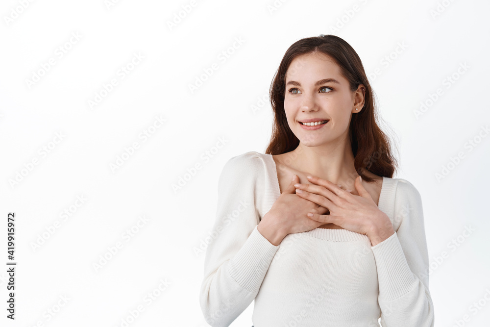 Pleased smiling woman keeps hands together on chest, expresses ...