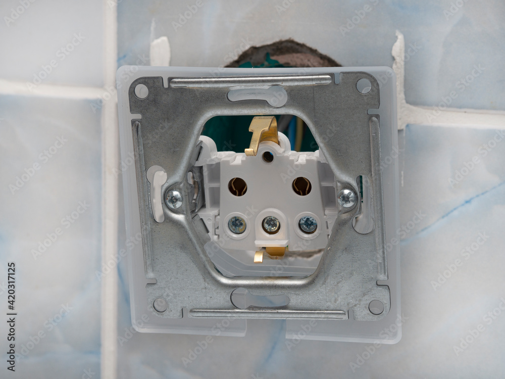 Disassembled, torn out electrical socket with bare wires in the ...