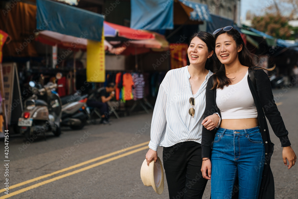 two asian japanese girls friends travelers holding hands walking by ...