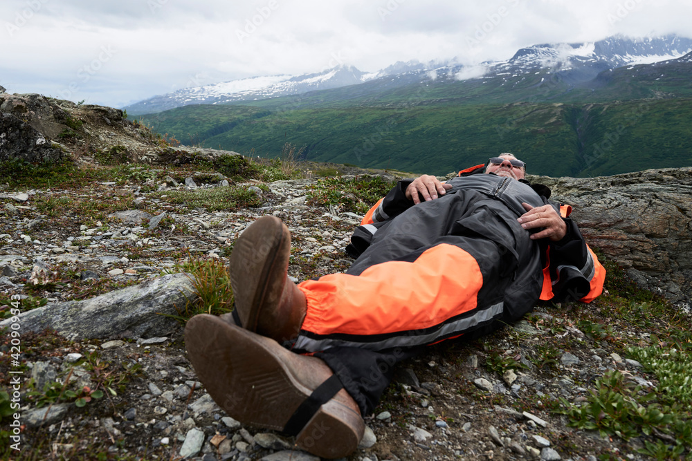 Senior male hiker taking a break lying on top of mountain, Valdez ...