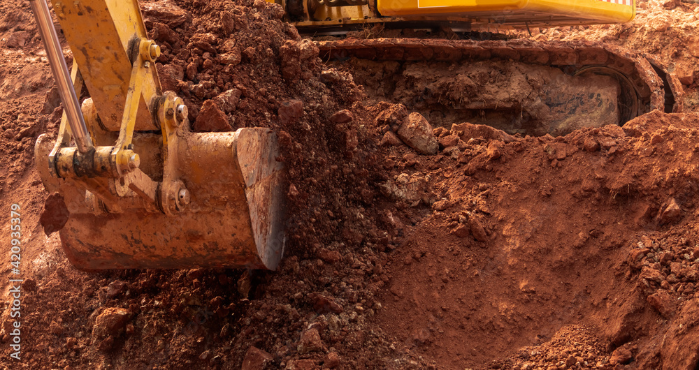 Backhoe working by digging soil at construction site. Bucket of backhoe ...