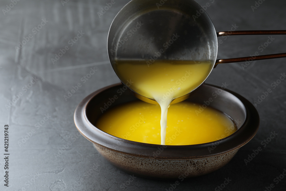 Pouring clarified butter into bowl on black table Stock Photo | Adobe Stock