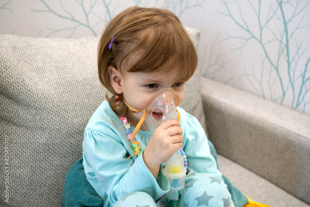 Kid girl makes inhalation with a nebulizer. sick child holding ...