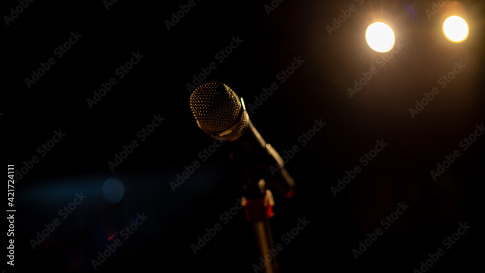 Side view of micrphone on stand sitting on empty stage with lights ...