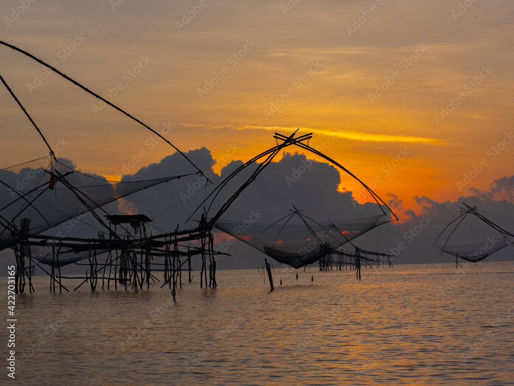Silhouette photo of fisherman trap fish in front of sunrise scene at ...