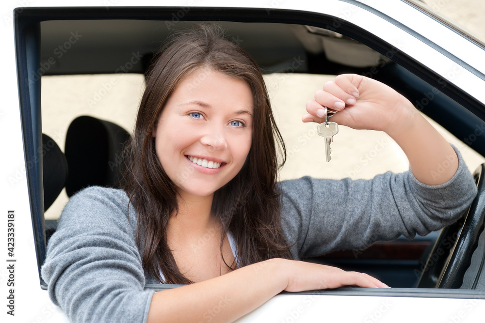 Beautiful young woman sitting in a car and showing the key, she is ...