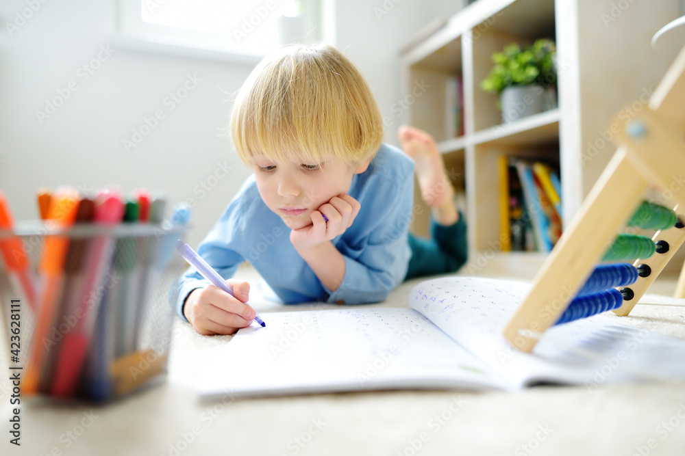 Elementary student boy doing homework at home. Child learning to count ...