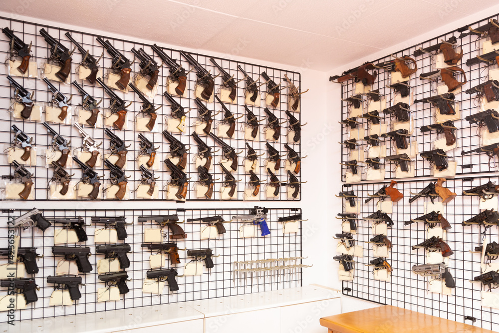 Gun shop interior with various handguns displayed on wall rack. Stock ...