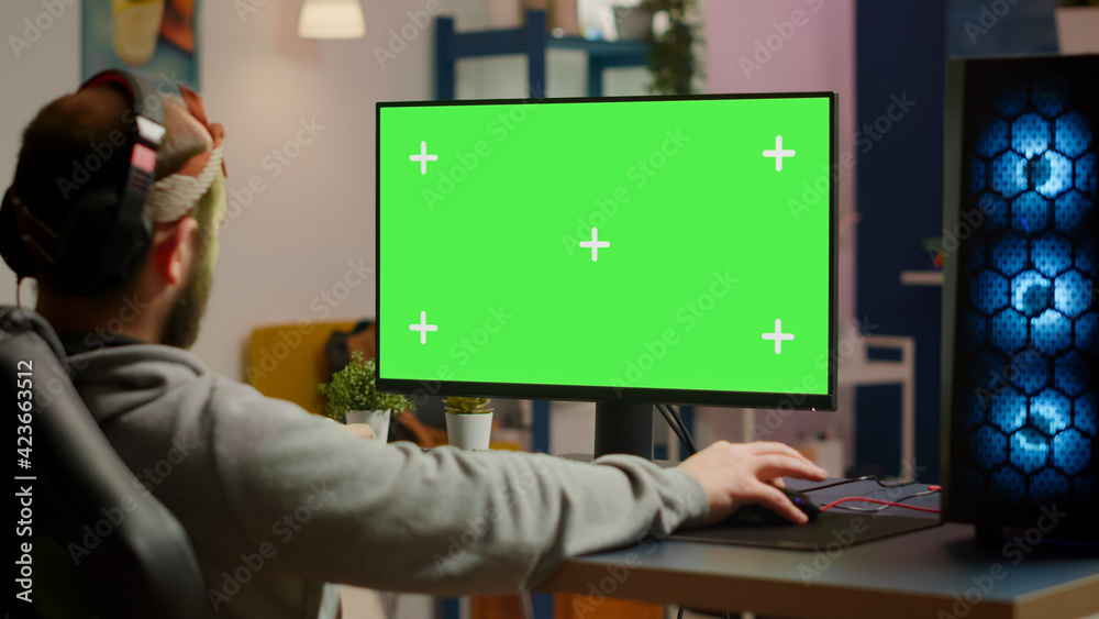 Gamer playing video games on powerful computer with green screen chroma ...