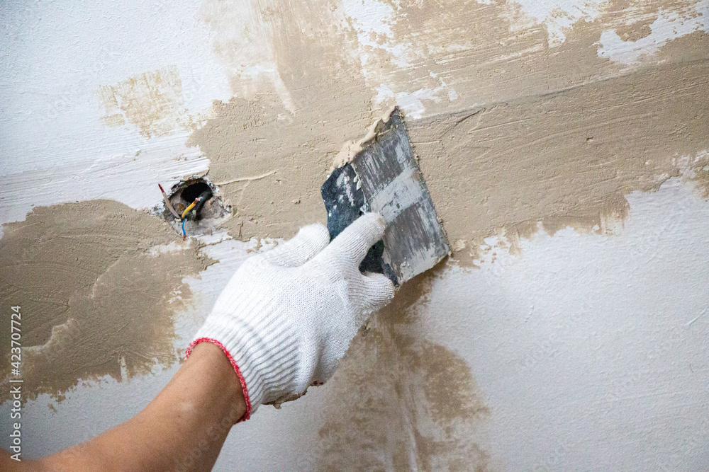 Foto mans hand in cloth glove with spatula and putty, applies mastic to ...