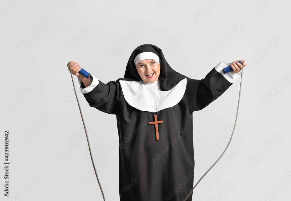 Senior nun with jumping rope on light background Stock Photo | Adobe Stock