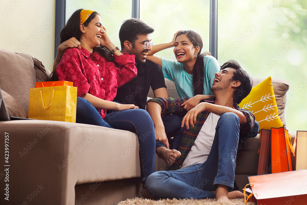 A Group of youngsters talking happily in living room after a shopping ...