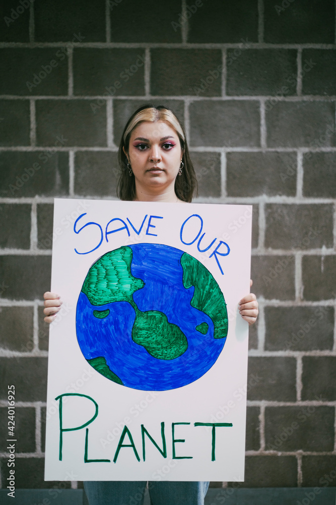 Female activist with planet earth poster standing against wall Stock ...