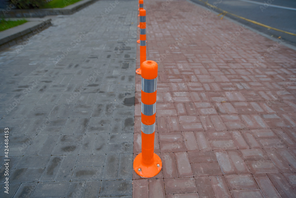 Striped orange reflictive traffic bollards placed in row for safety ...