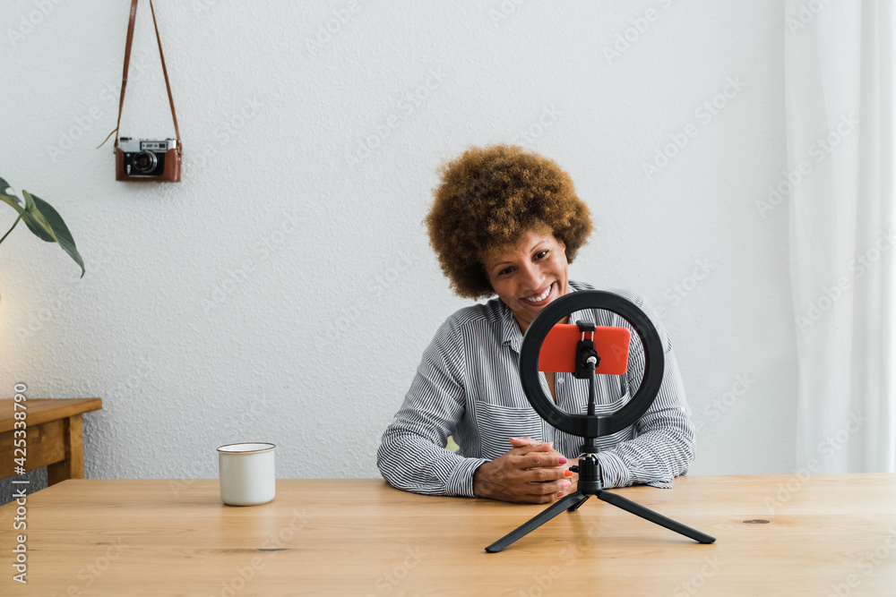 African woman streaming live video with smartphone in influencer led ...