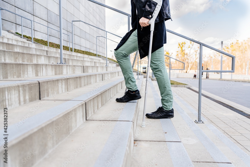 Injured man trying to walk on crutches up the stairs. Disability after ...