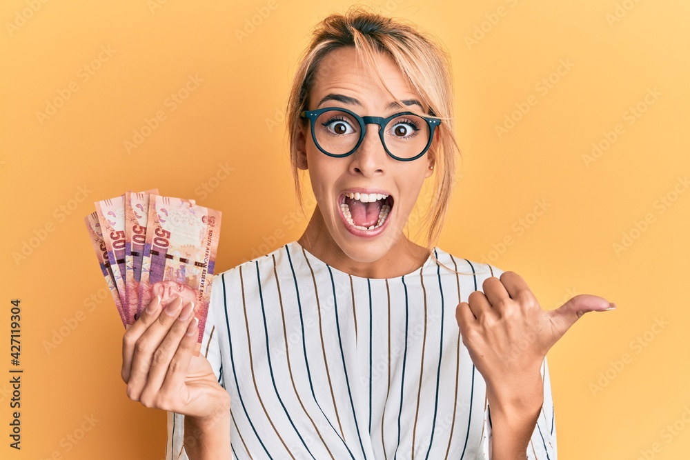 Beautiful blonde woman holding south african 50 rand banknotes pointing ...