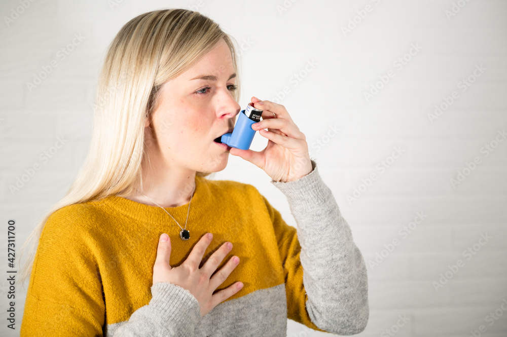 Young blonde woman using a blue asthma spray inhaler Stock Photo ...
