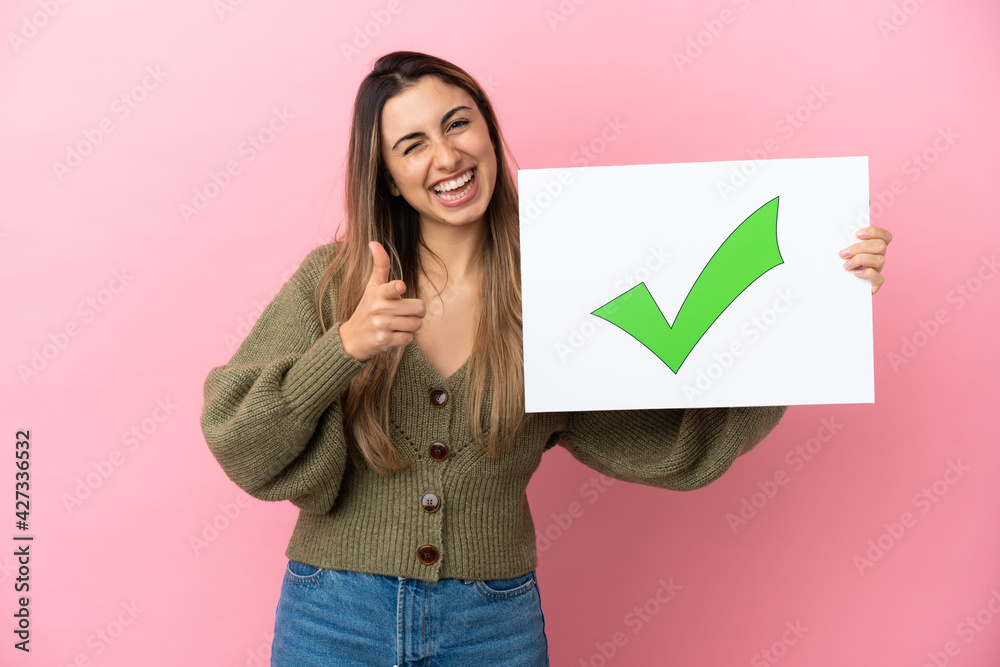 Young caucasian woman isolated on pink background holding a placard ...