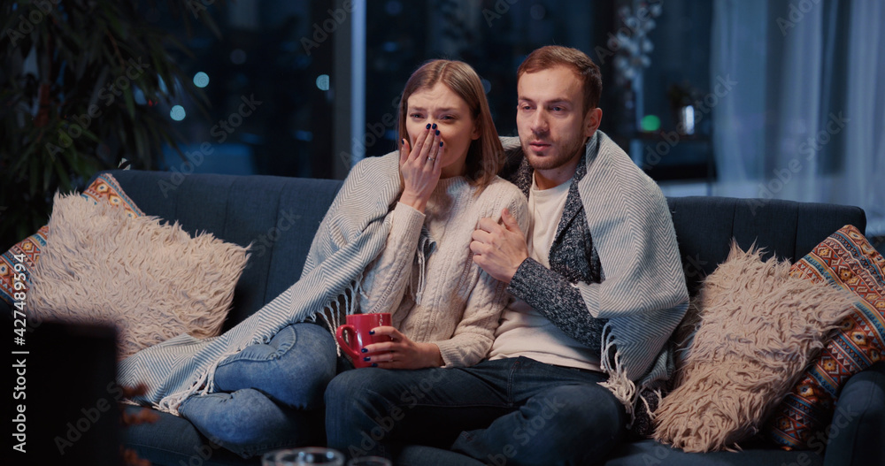 Emotional caucasian man and woman couple watching TV horror movie ...