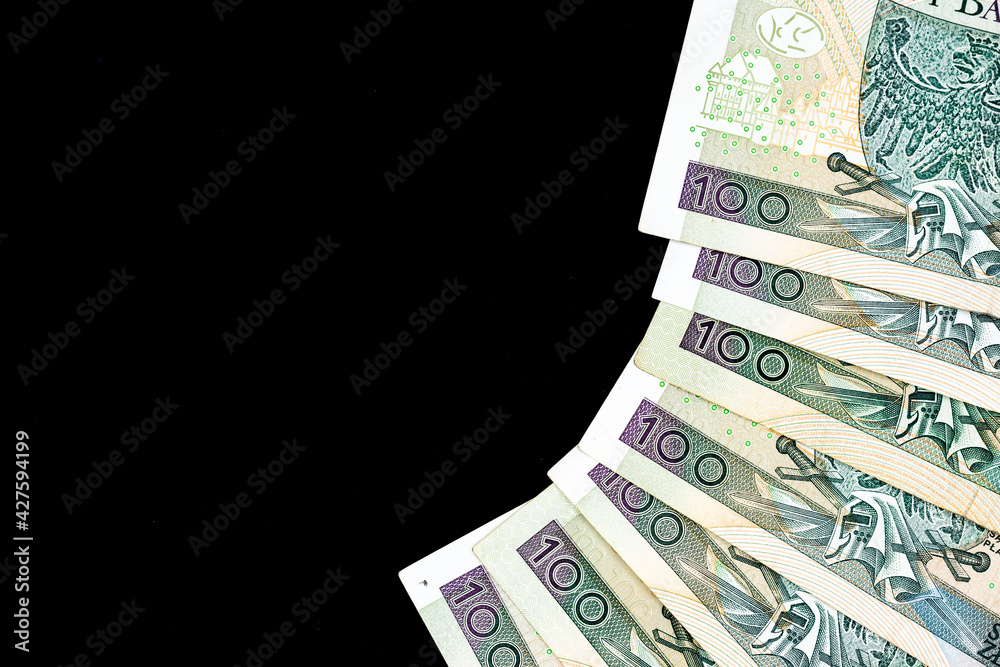 Polish banknotes of PLN 100 on a black background. Photo taken under ...
