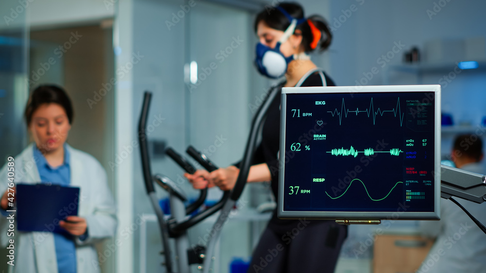 Monitor showing EKG scan of athlete running on cross trainer and ...