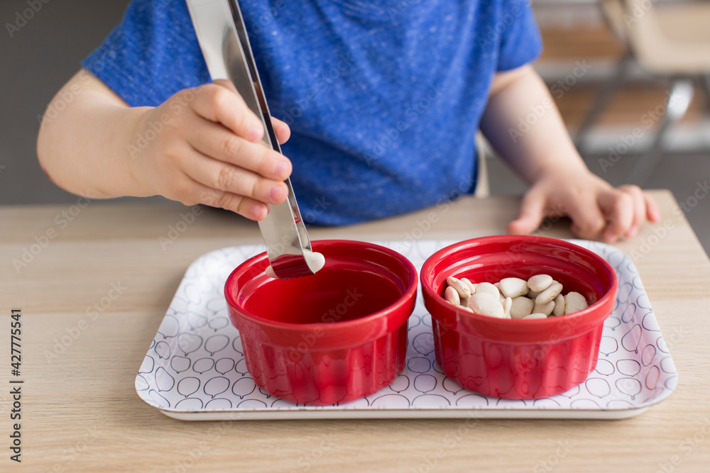 Little boy transferring beans into ceramic dishes while practicing ...