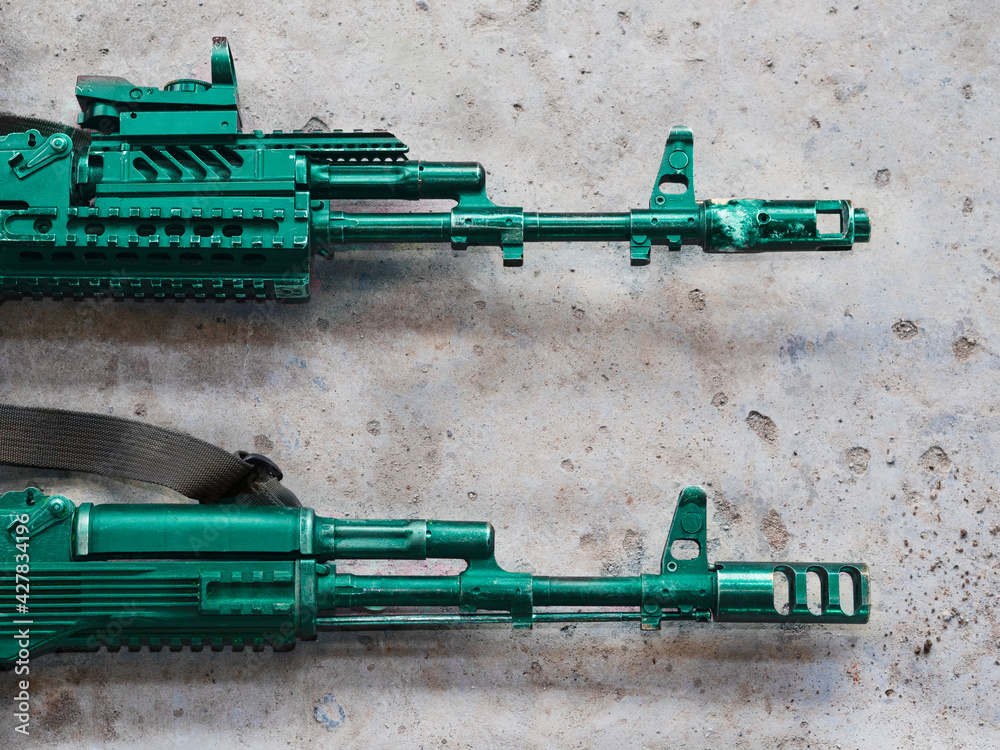Two custom green assault rifles close-up lying on the concrete floor ...