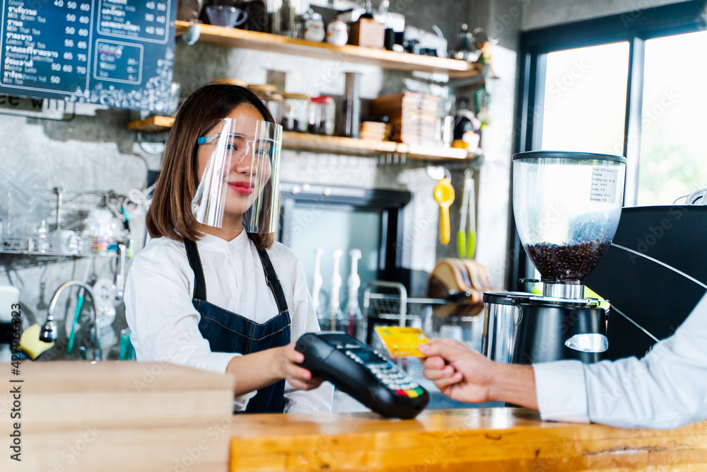 Asian female cashier receiving contactless credit card payment from ...