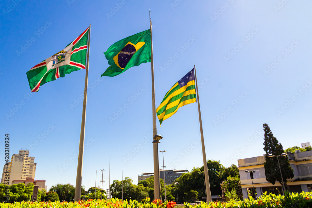 Três bandeiras hasteadas e céu azul ao fundo. Bandeira do Brasil, do ...