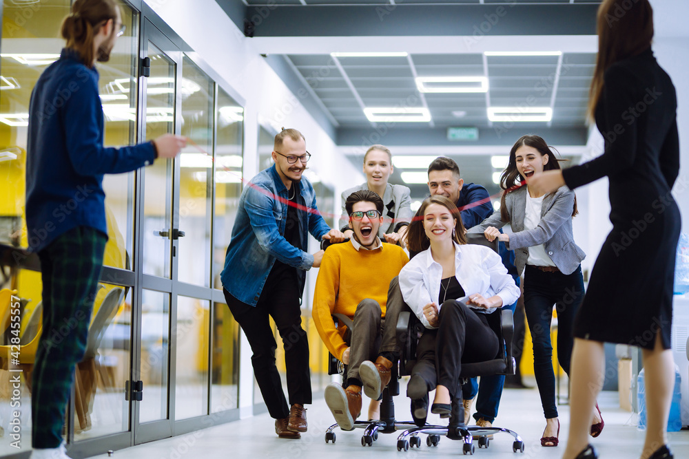 Friendly work team ride chairs in office room cheerfully excited ...