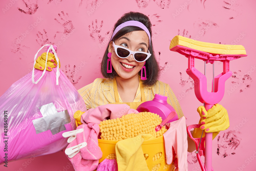 Happy satisfied housewife cleans house carries mop and trash bag gives ...