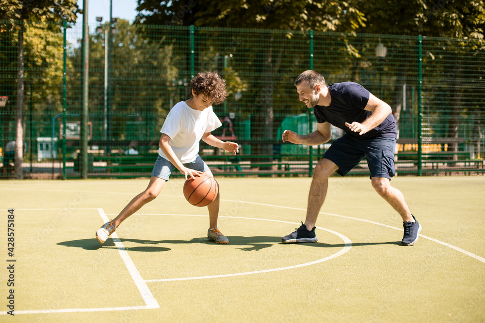 Sportive dad teaching his son how to play basketball outside Stock ...