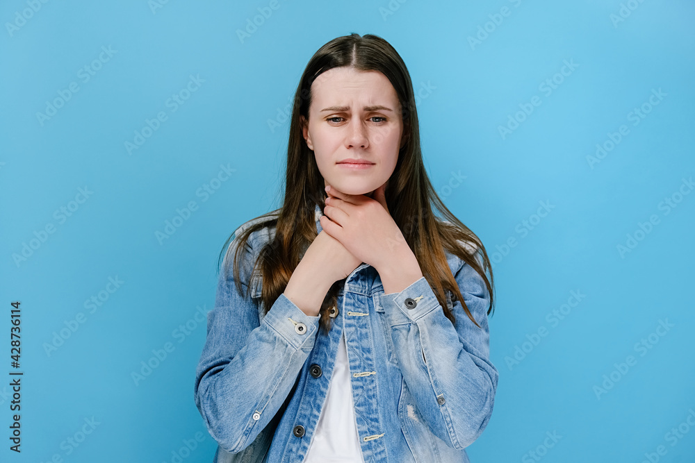Unhappy sick young woman touches neck, suffers from sore throat, has ...