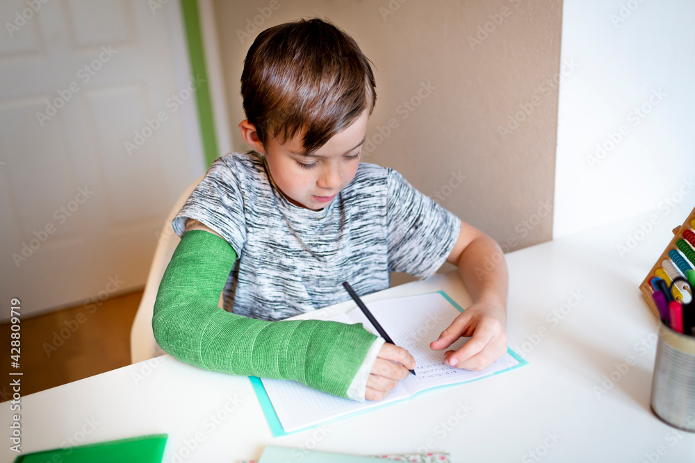 cool boy with green arm cast is sitting in his room and is writing ...