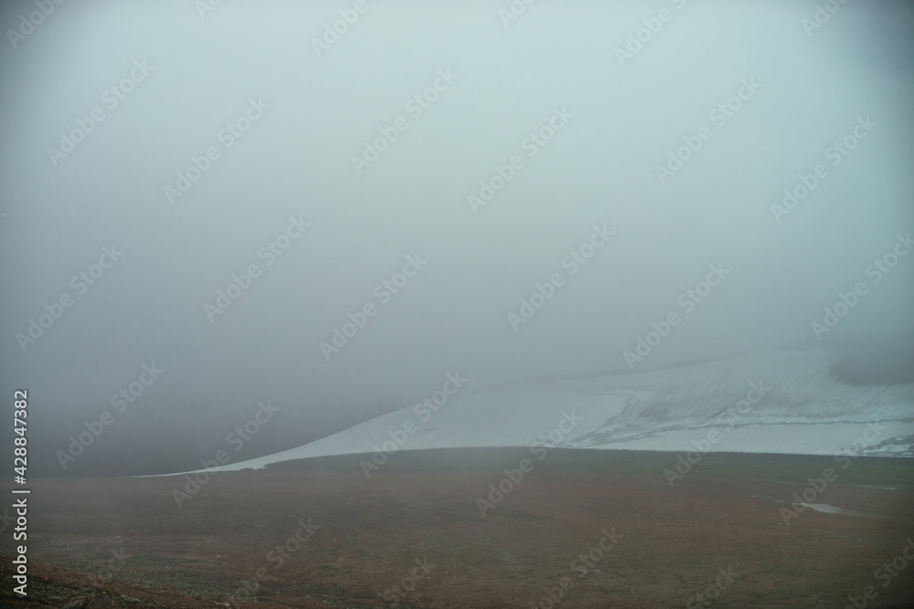 Atmospheric minimalist mountain landscape with small glacier on rocky ...